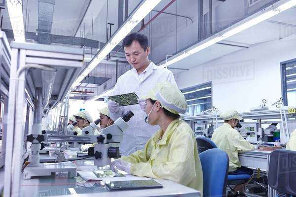 Supervisor overseeing quality check station at factory producing ...