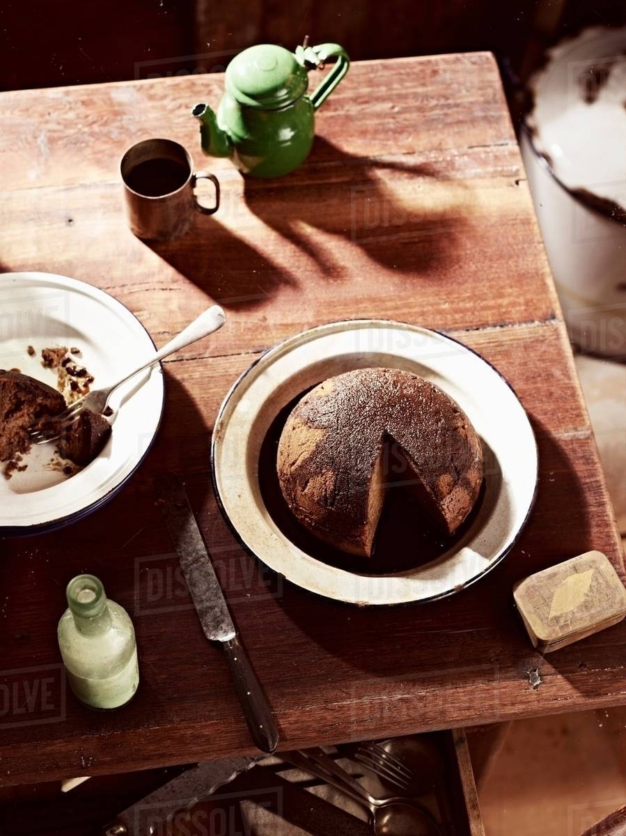 Rustic table with dish of steamed treacle pudding and teapot - Royalty ...