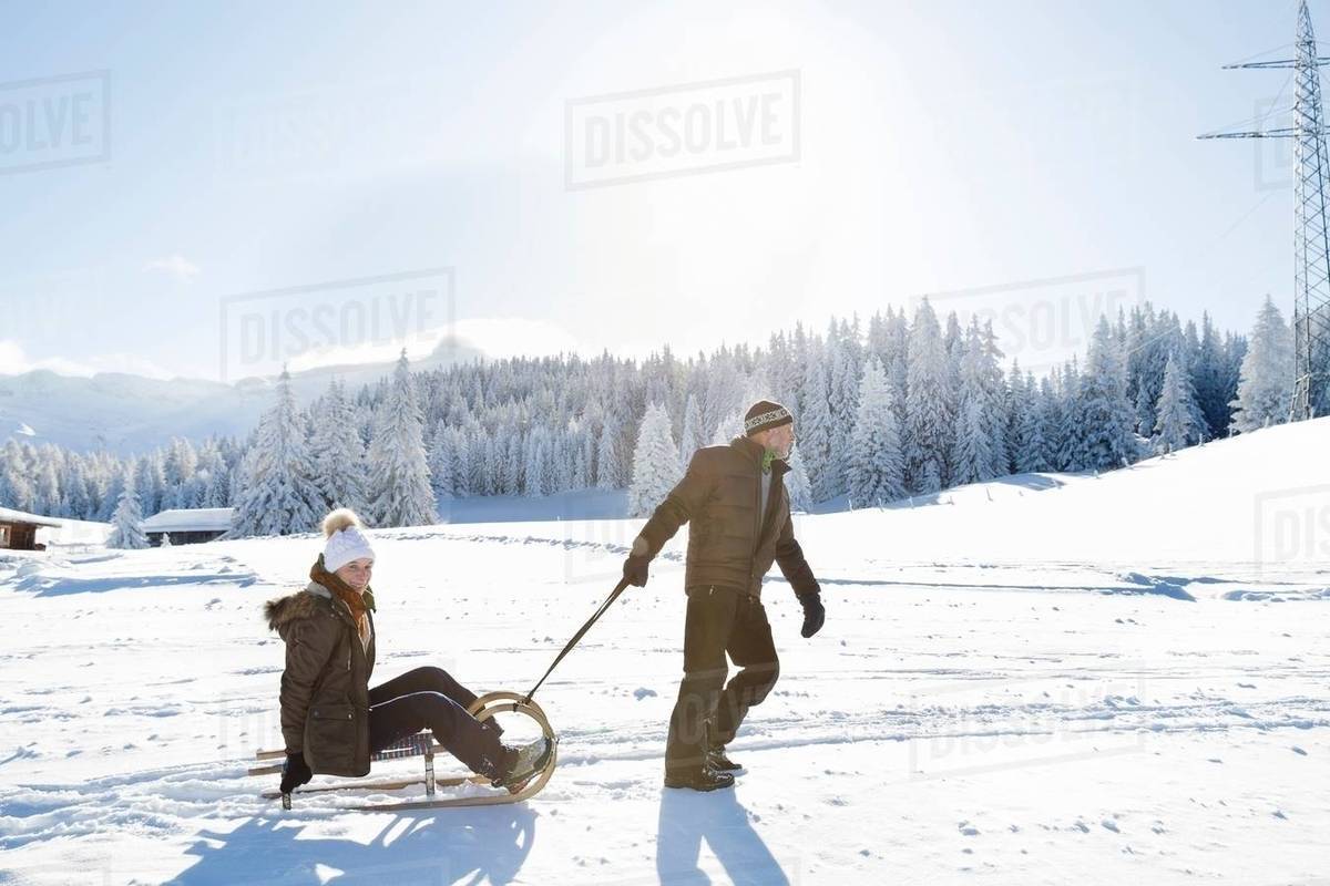 Side view of senior man pulled senior woman on sledge, Sattelbergalm ...