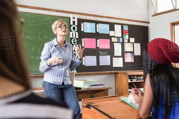 Female teacher addressing students in classroom - Royalty-free Stock ...