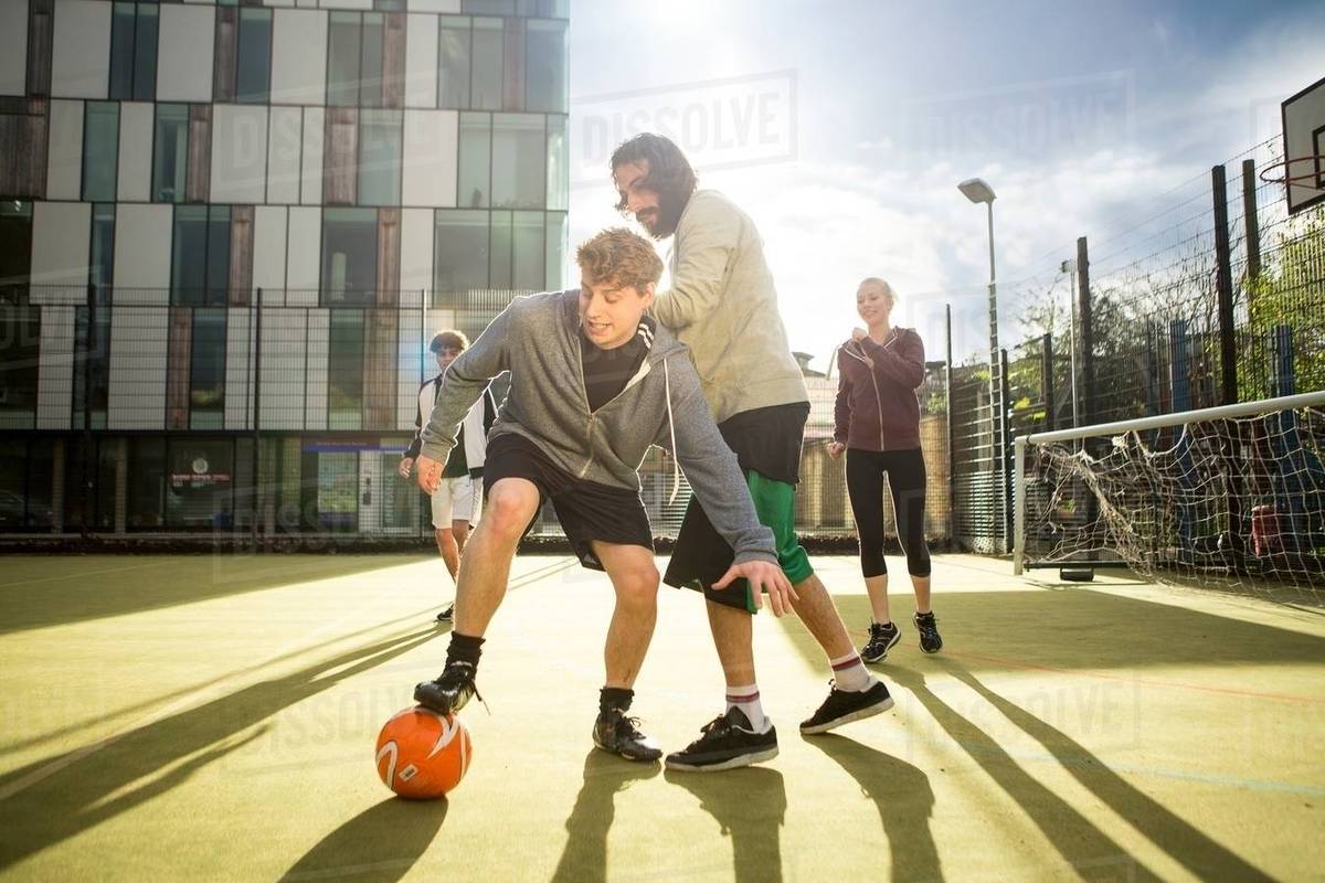 Group of adults playing football on urban football pitch - Royalty-free ...