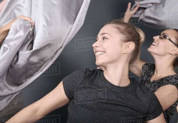 Young women holding cloth over head, grey background - Stock Photo ...
