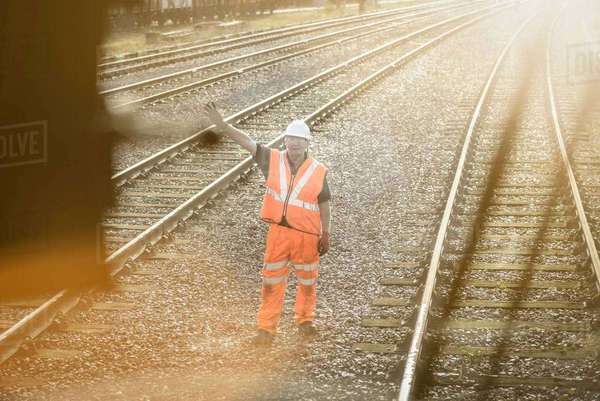 Railway worker signalling to train on railway - Stock Photo - Dissolve