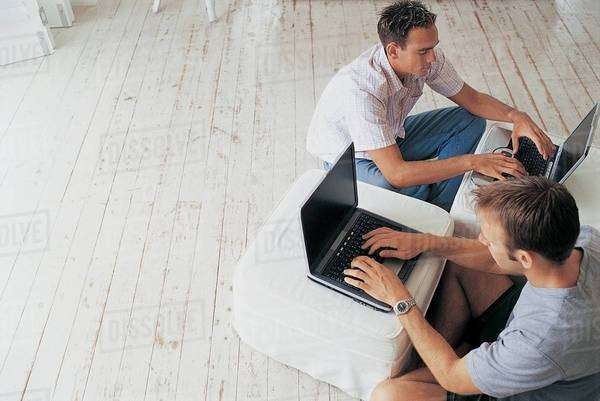 Men using laptops in living room - Royalty-free Stock Photo | Dissolve