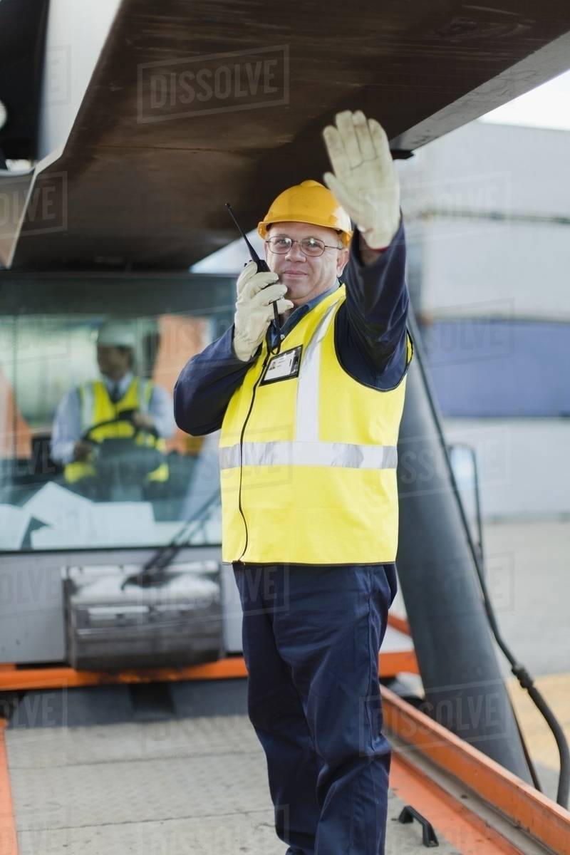 Worker directing machinery on site - Royalty-free Stock Photo | Dissolve