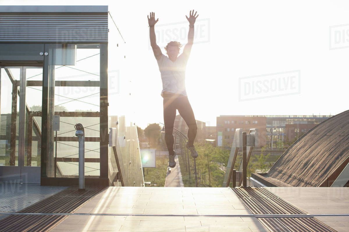Man training, jumping mid air on footbridge - Stock Photo - Dissolve