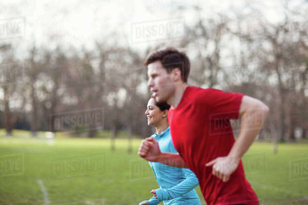 Young man and woman running together in park - Royalty-free Stock Photo ...
