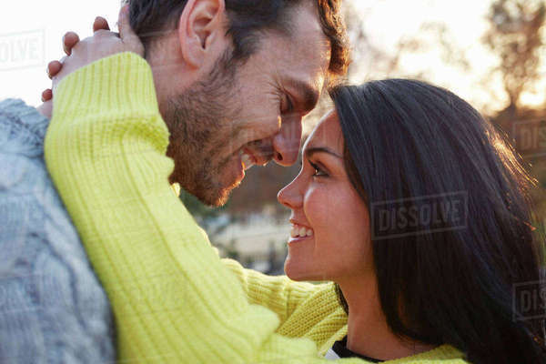 Woman with arms around man face to face smiling - Stock Photo - Dissolve