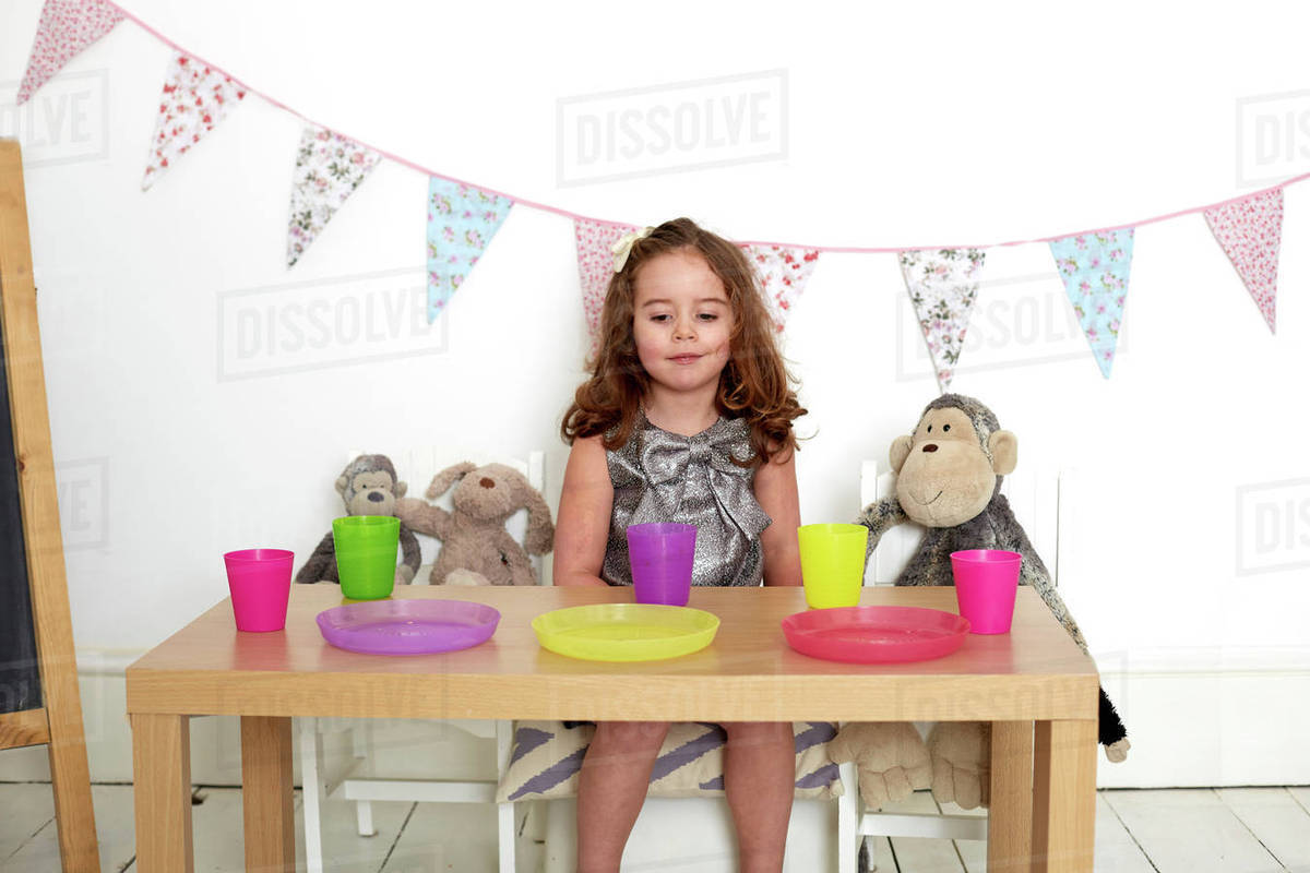 Happy girl at tea party with soft toys - Stock Photo - Dissolve