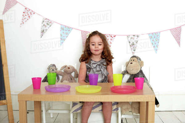 Happy girl at tea party with soft toys - Stock Photo - Dissolve