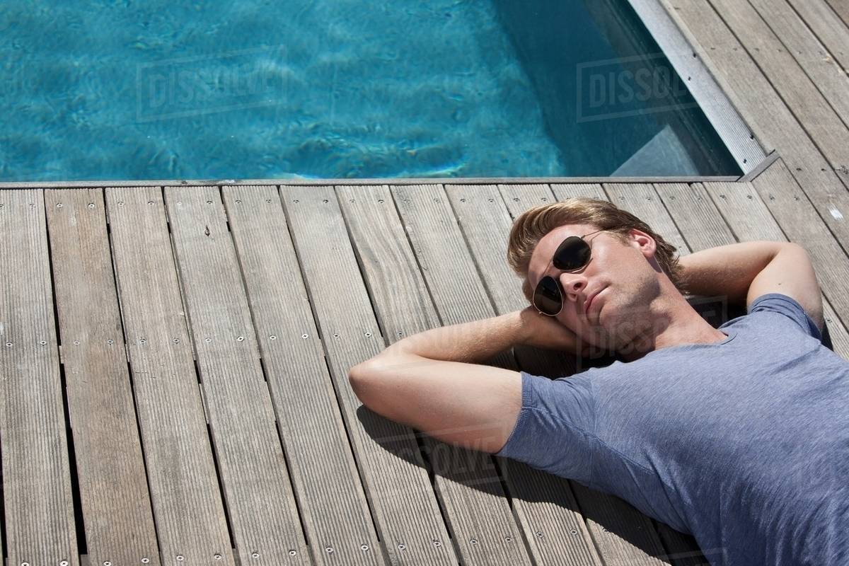 Man relaxing by swimming pool - Royalty-free Stock Photo | Dissolve