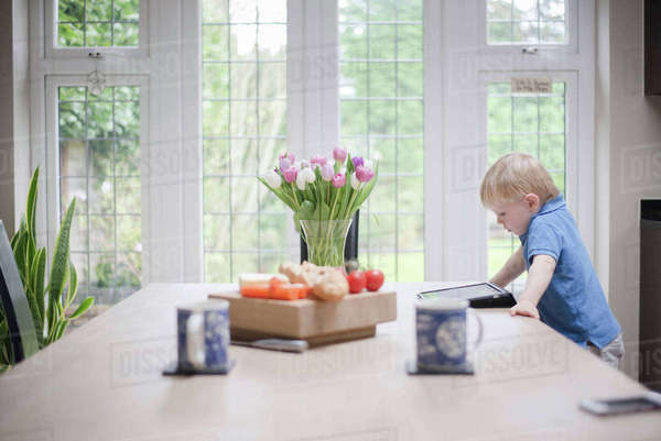 Young boy standing at table looking at digital tablet - Royalty-free ...
