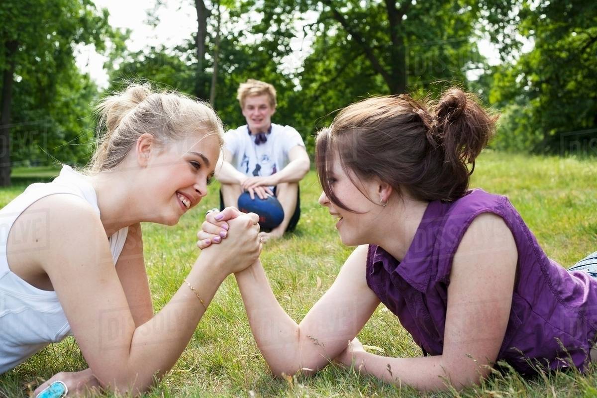 Teenage girls arm wrestling in grass - Royalty-free Stock Photo | Dissolve