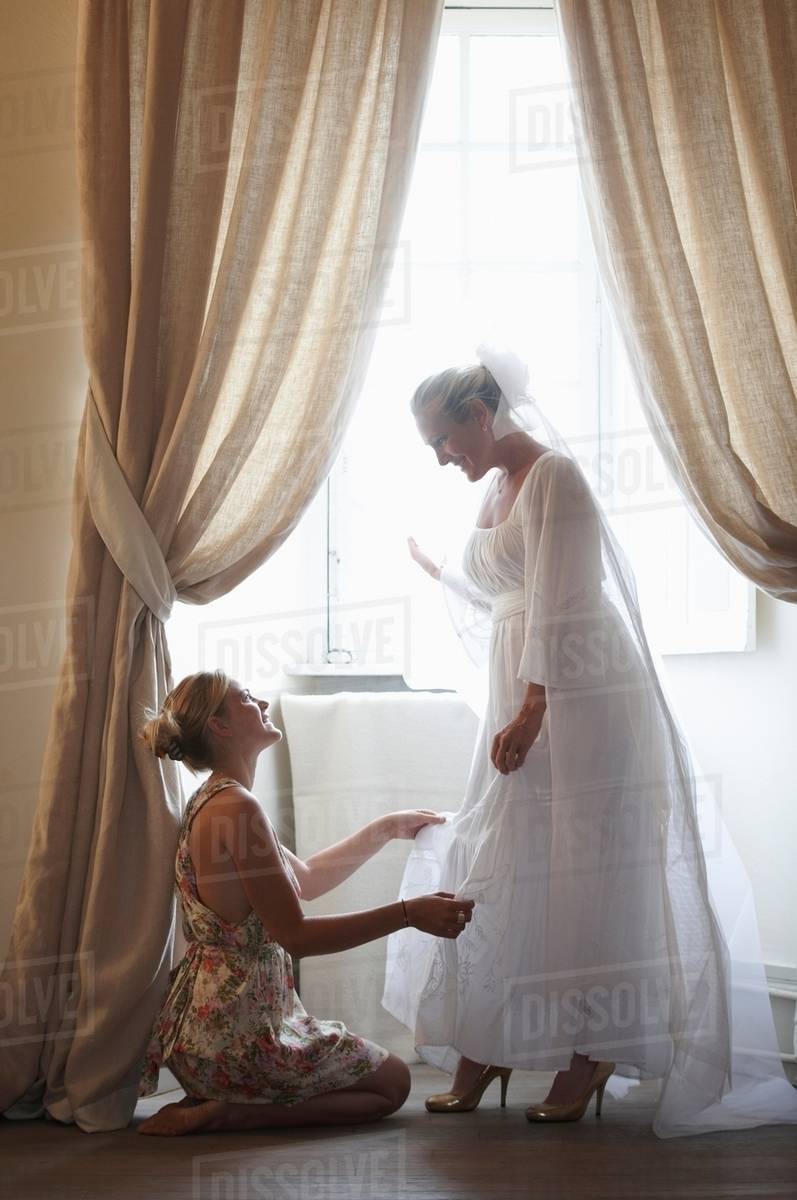 Woman helping bride get dressed - Stock Photo - Dissolve