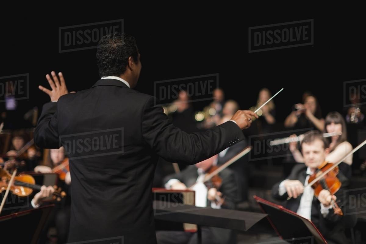 Conductor waving baton over orchestra - Stock Photo - Dissolve