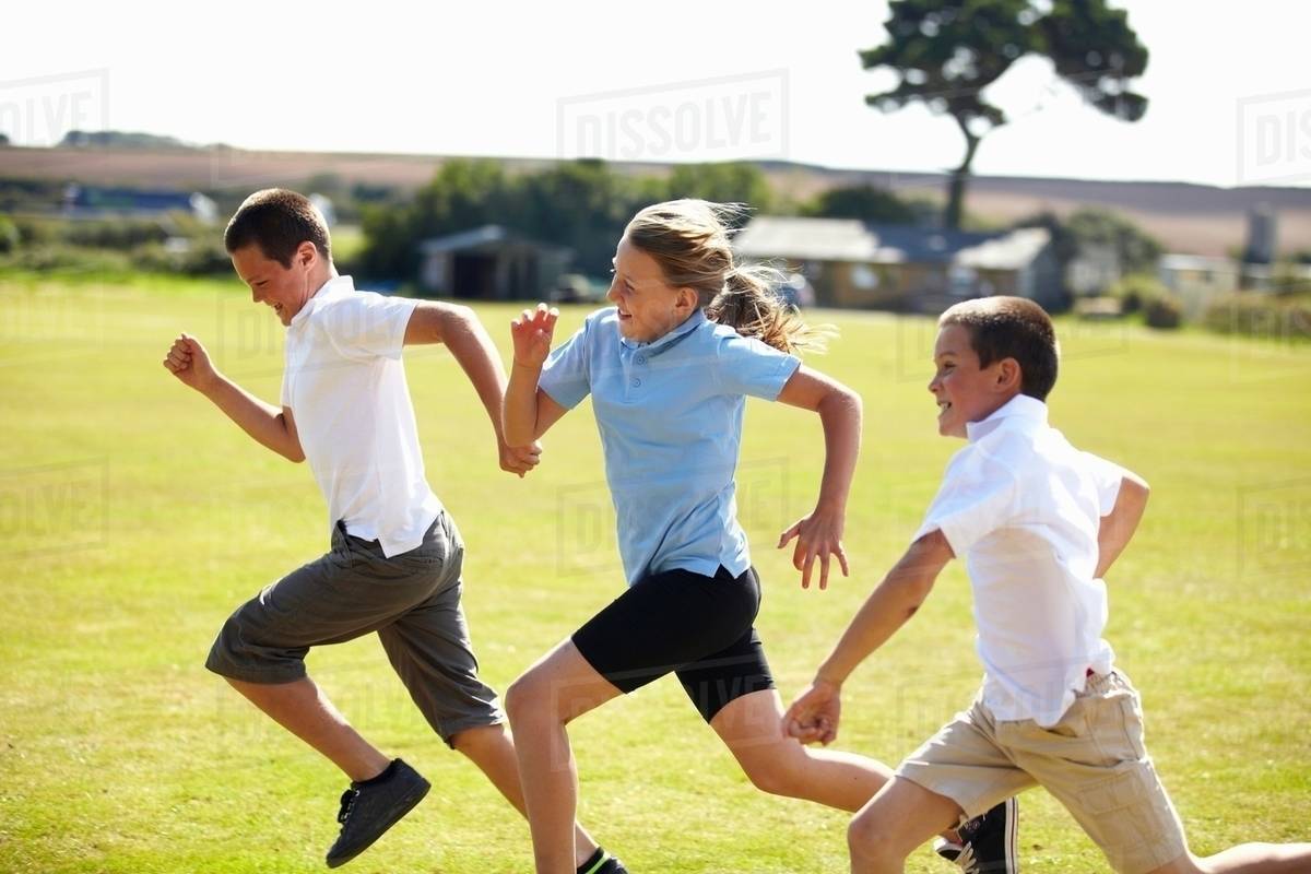 Smiling children racing in field - Stock Photo - Dissolve
