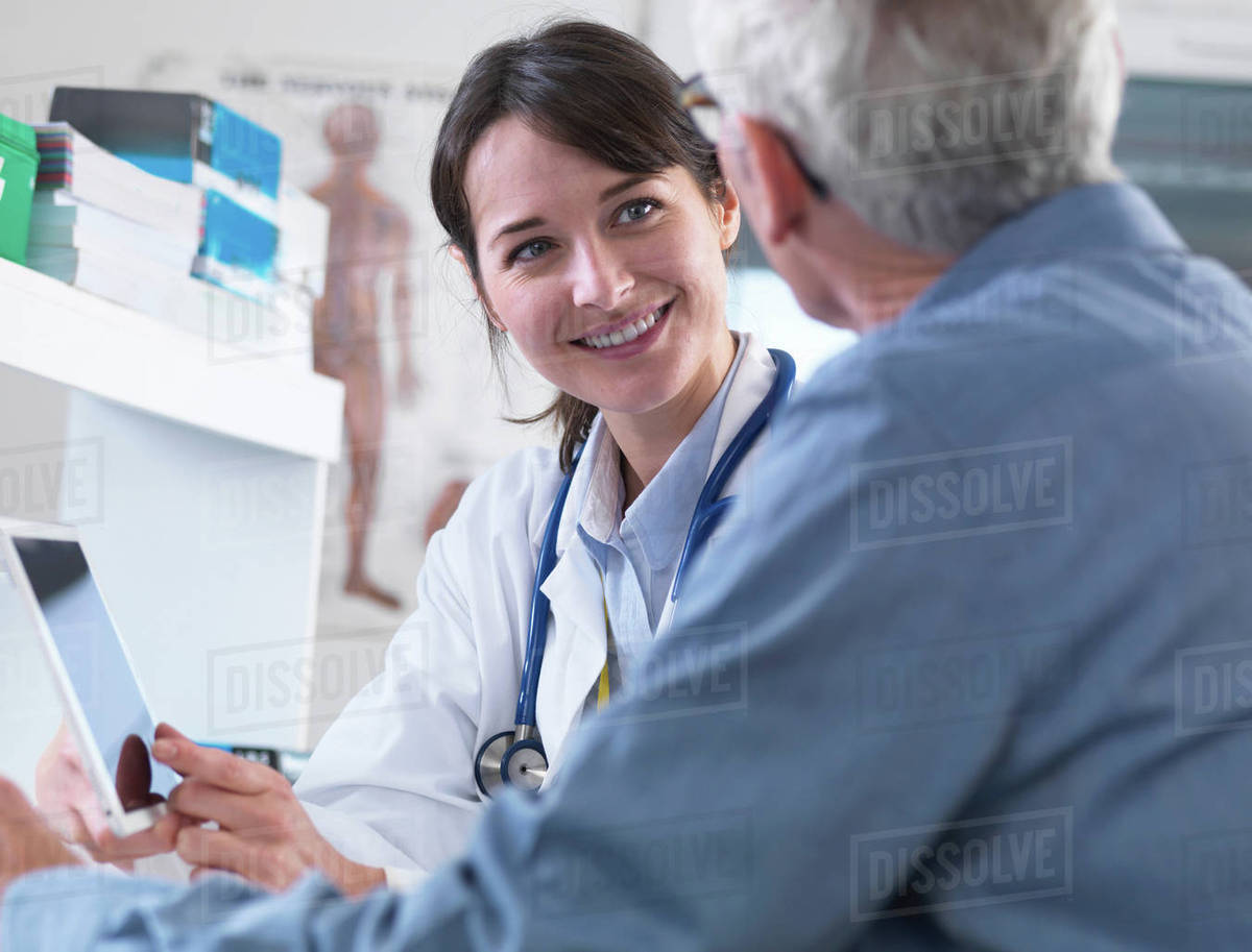 Doctor sharing health information on digital tablet with patient in ...