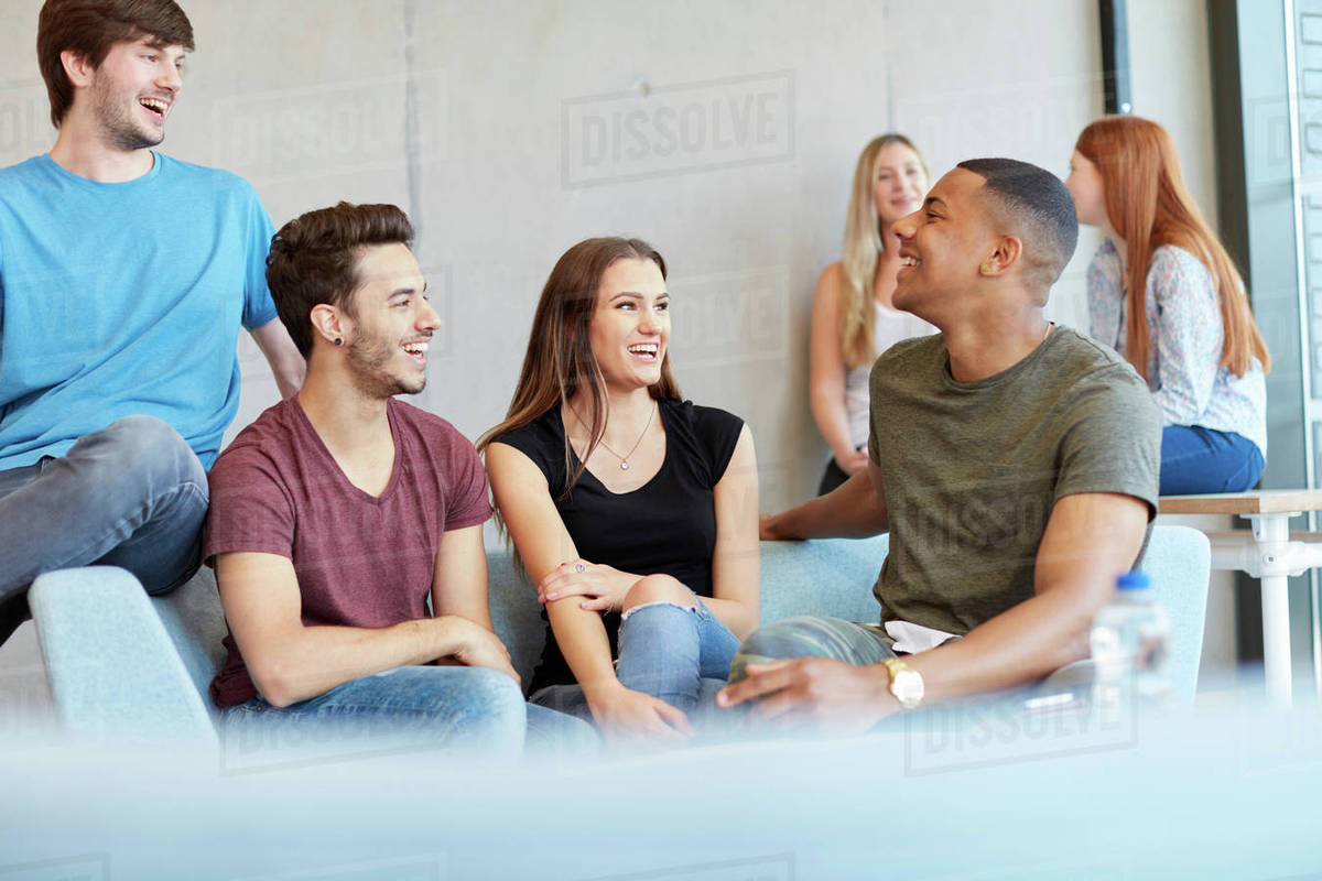 Group of young male and female students sitting on study space sofa ...