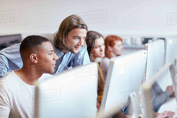 Male lecturer showing student using computer in higher education ...