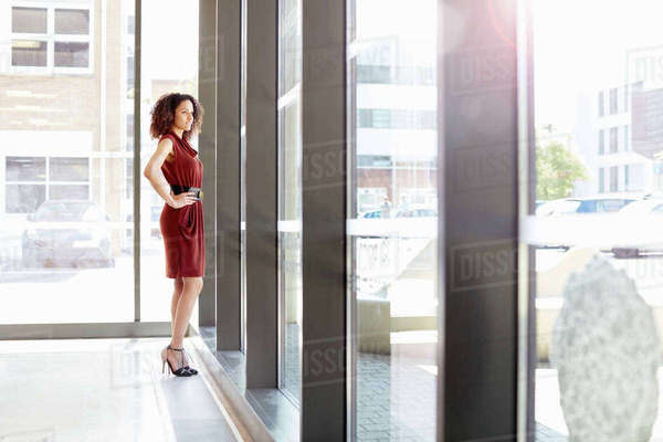 Confident young businesswoman looking out at office window - Royalty ...