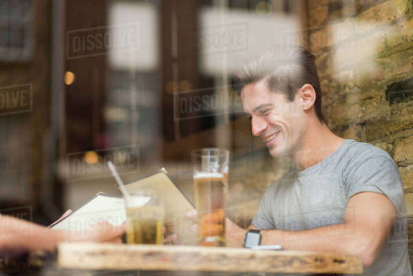 Window view of young man reading menu in restaurant - Stock Photo ...