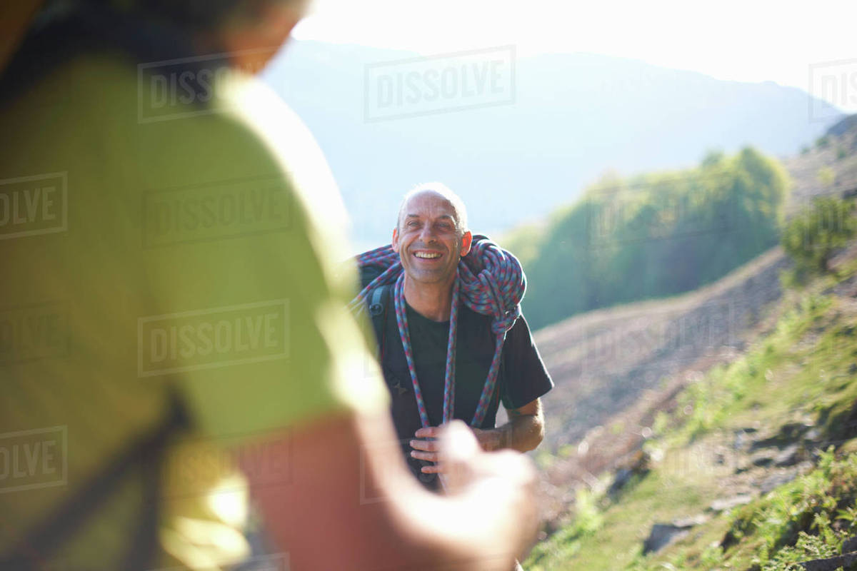 Rock climber carrying rope on shoulders smiling - Stock Photo - Dissolve