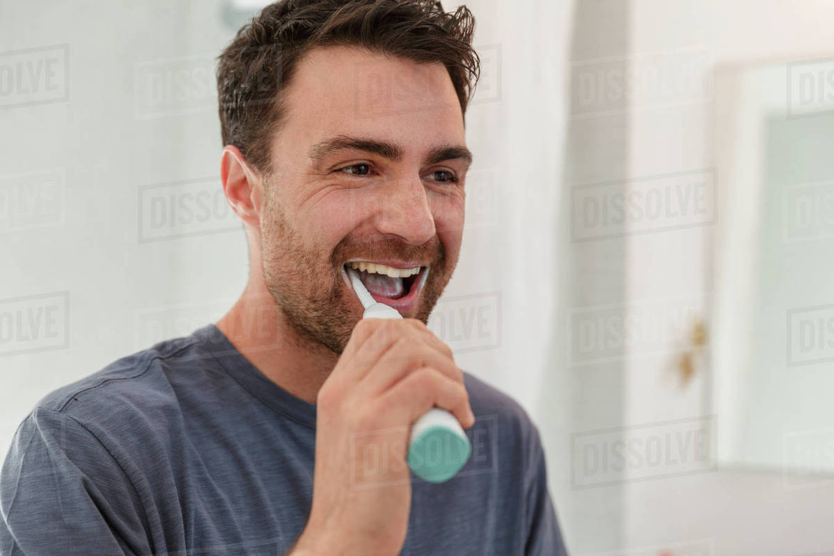 Man brushing teeth smiling - Stock Photo - Dissolve