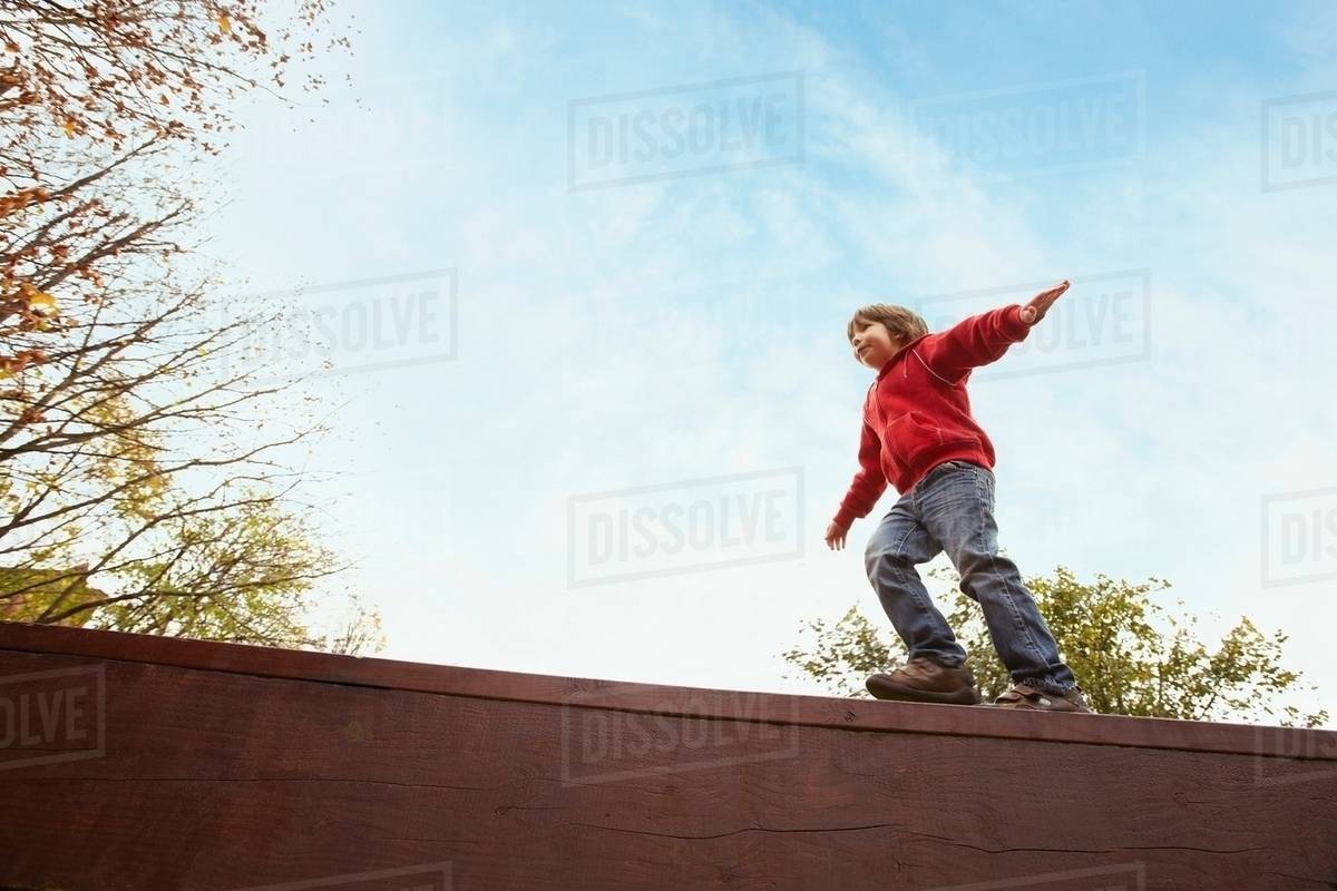 Boy balancing on wooden wall - Royalty-free Stock Photo | Dissolve