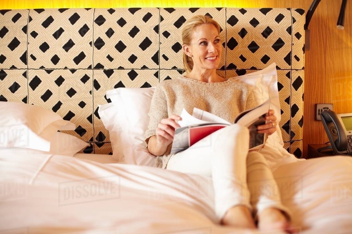 Woman reading magazine on bed - Stock Photo - Dissolve