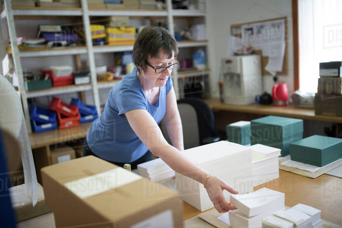 Female worker packing stacked paper in printing press workshop ...