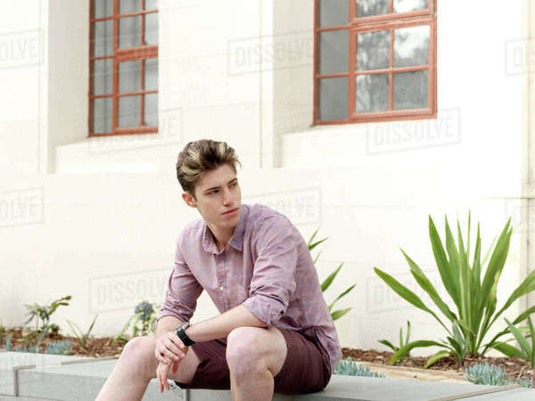 Young man sitting on step, outdoors, looking away - Stock Photo - Dissolve