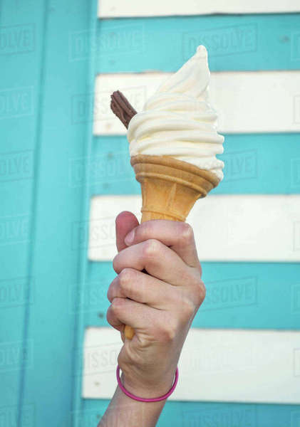 Cropped view girl's hand holding ice cream - Stock Photo - Dissolve