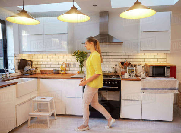 Mid adult woman walking in stylish kitchen - Royalty-free Stock Photo ...