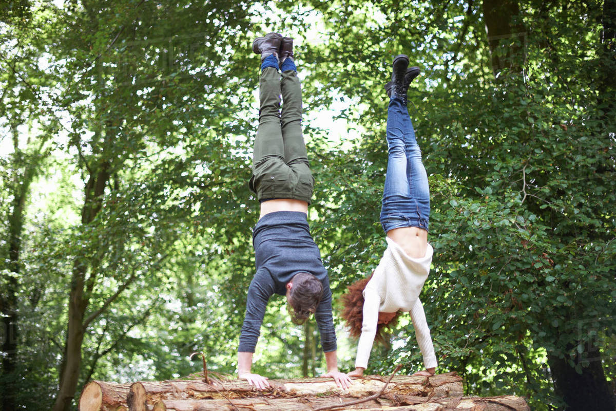 Couple in forest doing handstand on fallen tree - Royalty-free Stock ...