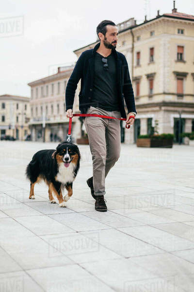 Mid adult man walking dog at city square - Royalty-free Stock Photo ...