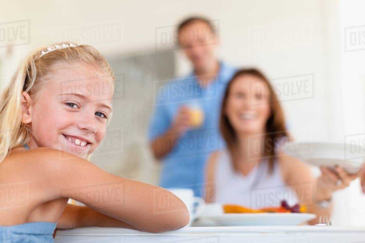 Smiling girl sitting at table - Stock Photo - Dissolve