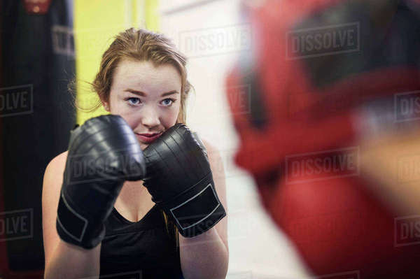 Young female boxer poised to box punch mitt - Stock Photo - Dissolve
