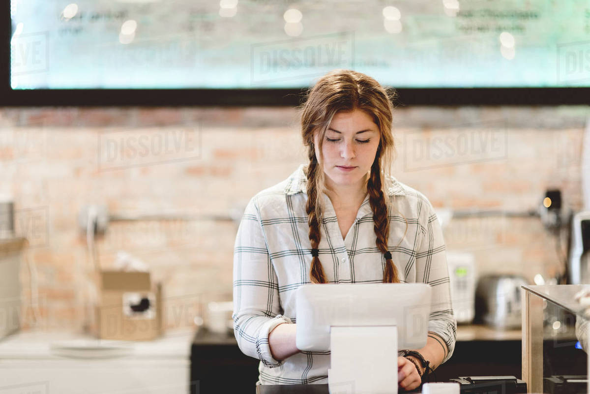 Cashier using cash register in cafe - Royalty-free Stock Photo | Dissolve