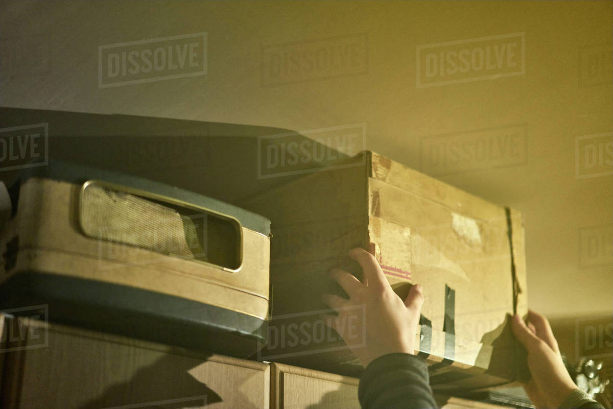 Hands of boy reaching to remove cardboard box from shelves - Royalty ...