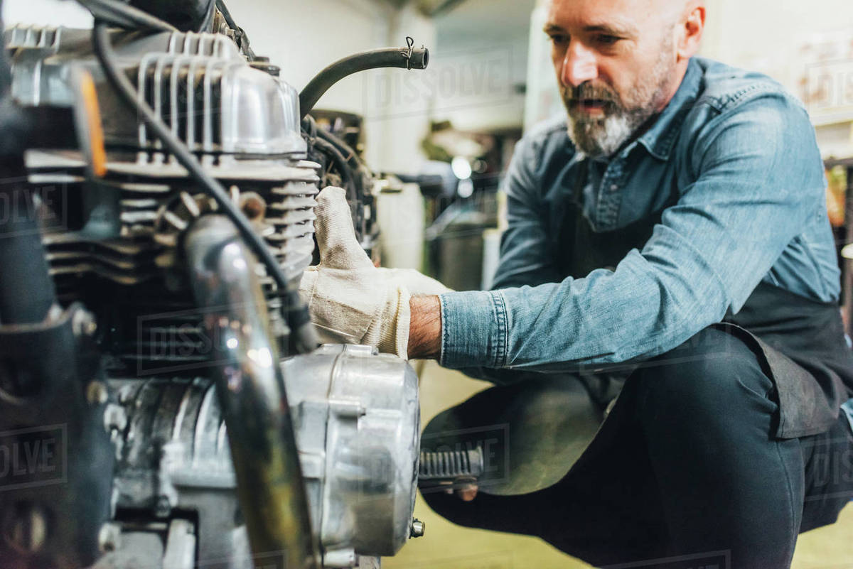 Mature man, working on motorcycle in garage - Royalty-free Stock Photo ...