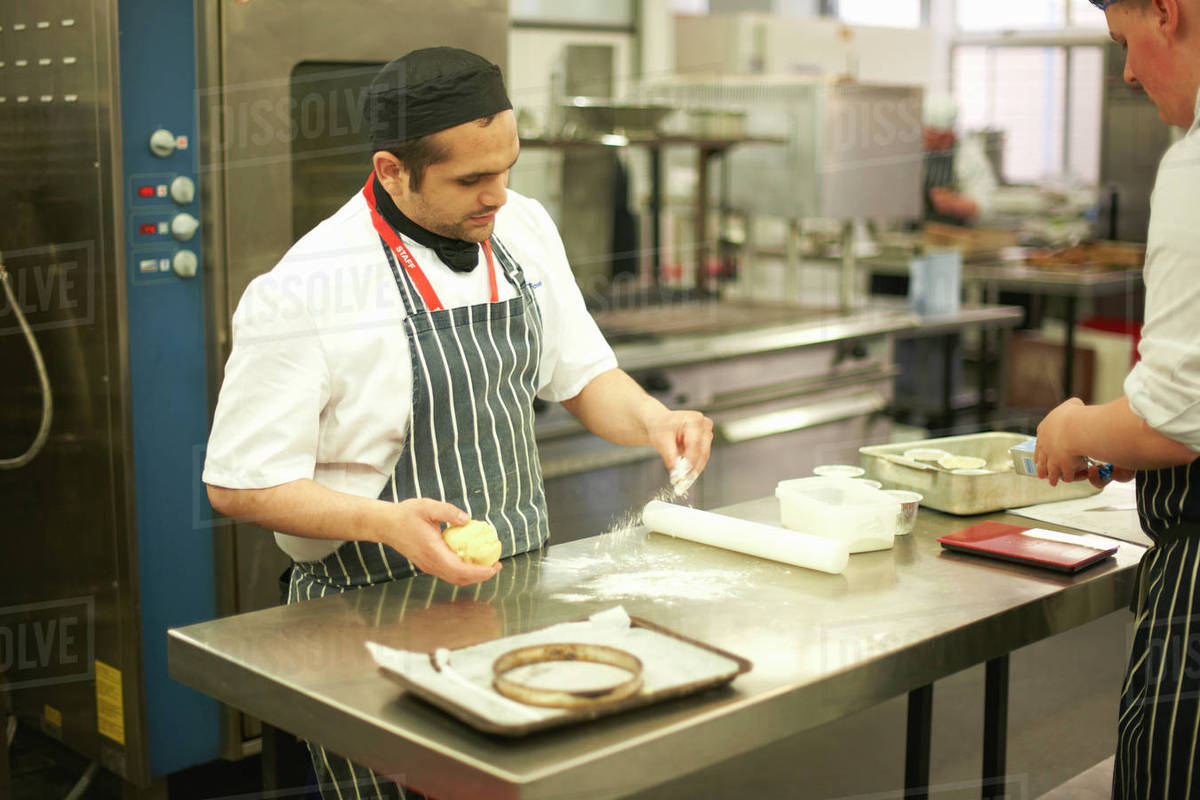 Chef lecturer demonstrating technique to teenage catering student at ...