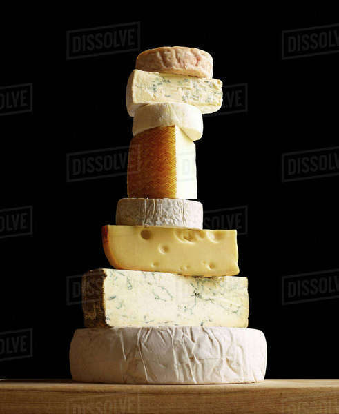 Stack of selection of cheeses, against black background - Stock Photo ...