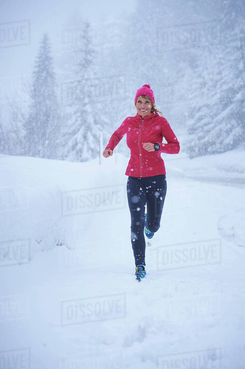 Female runner running in falling snow, Gstaad, Switzerland - Royalty ...