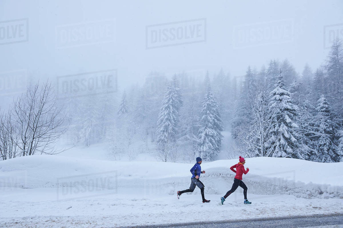Distant view of female and male runners running in deep snow, Gstaad ...