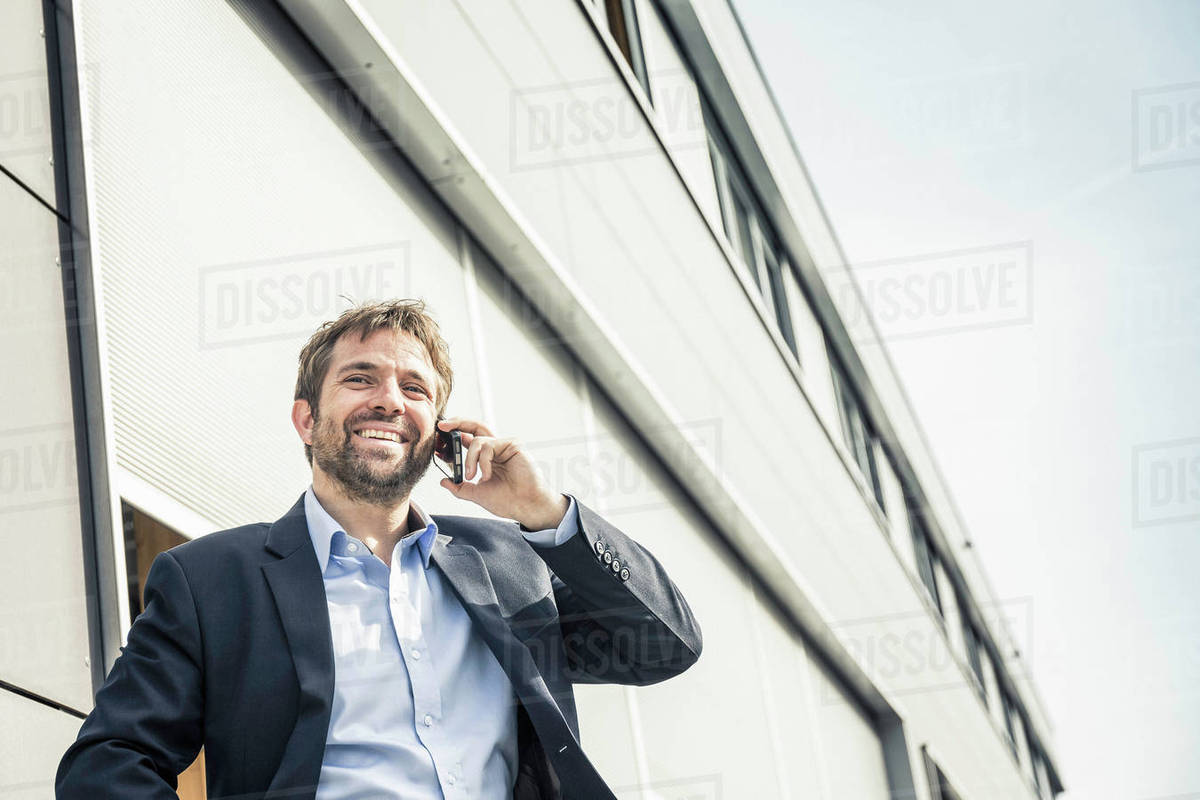 Businessman making smartphone call outside office building - Royalty ...