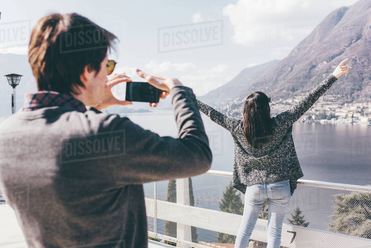 Man photographing girlfriend at lakeside, Monte San Primo, Italy ...