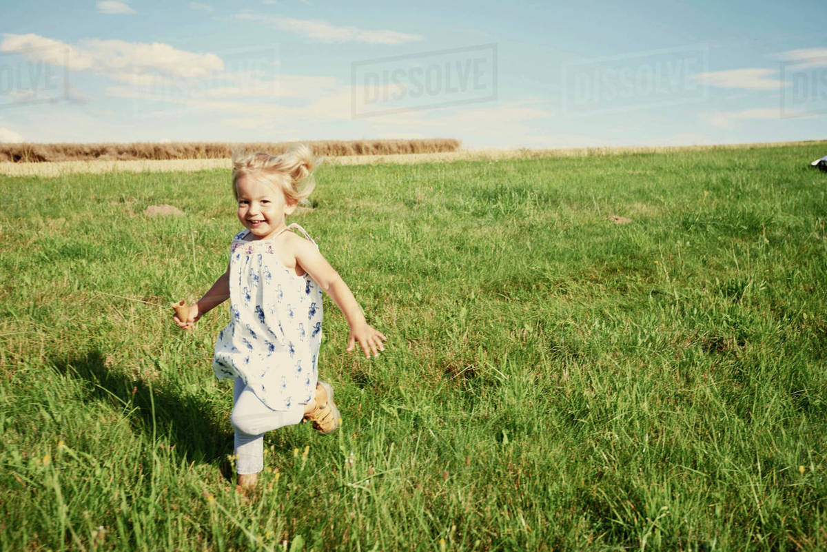Female toddler running in field - Royalty-free Stock Photo | Dissolve