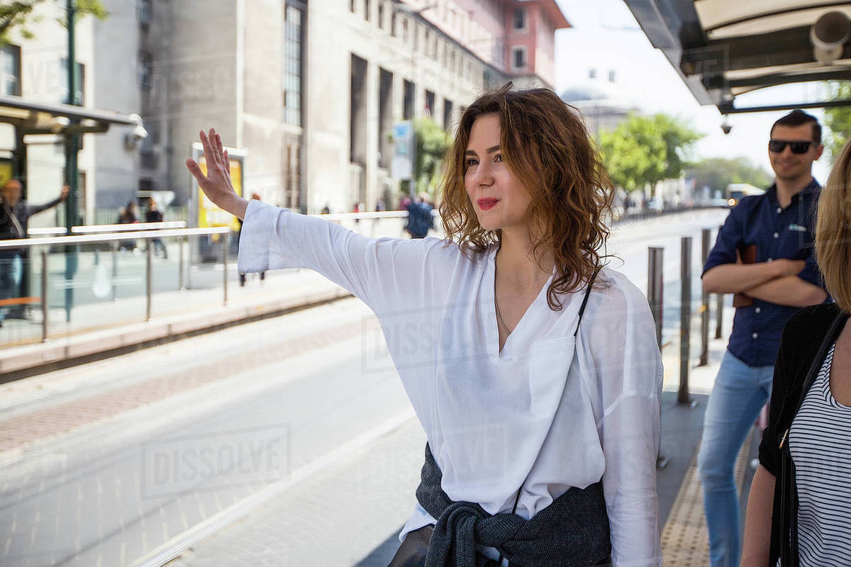 Young woman hailing a bus at city bus stop, Beyazit, Turkey - Royalty ...