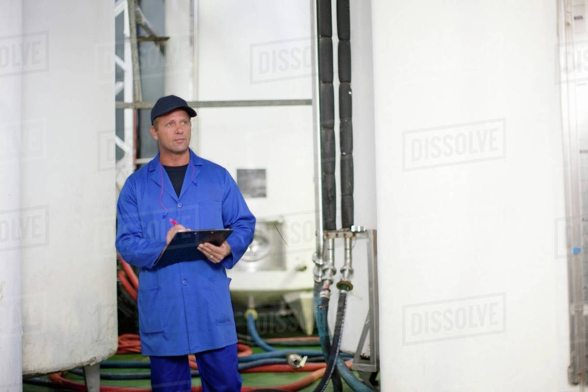 Worker writing on clipboard in factory - Royalty-free Stock Photo ...