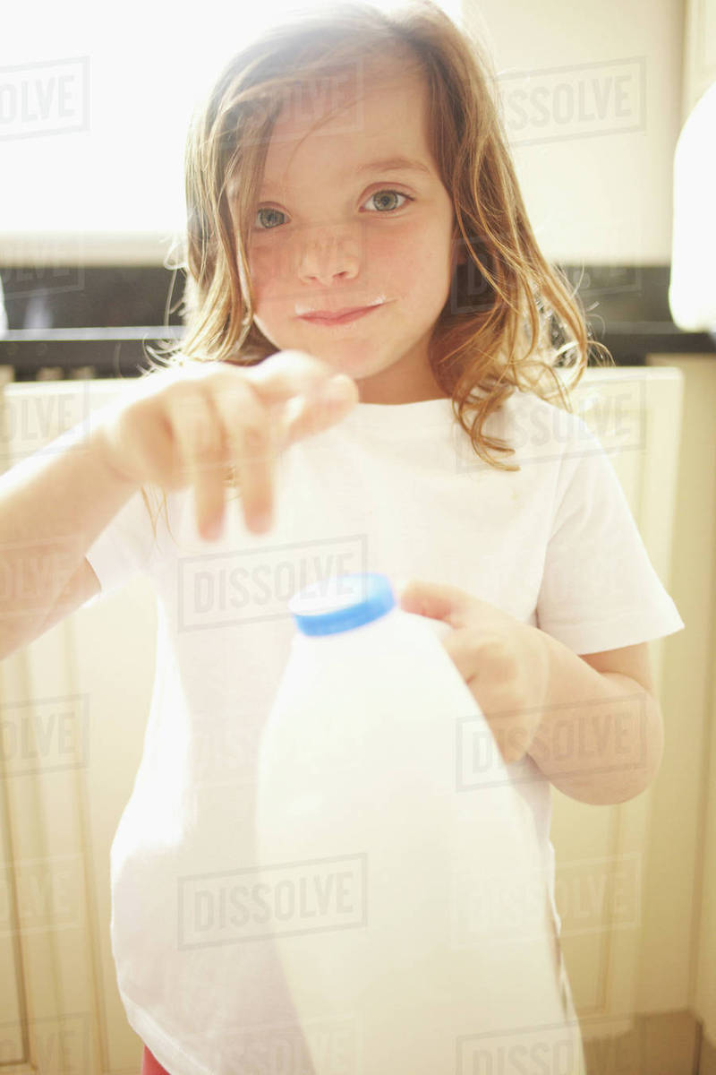 Girl opening jug of milk - Stock Photo - Dissolve